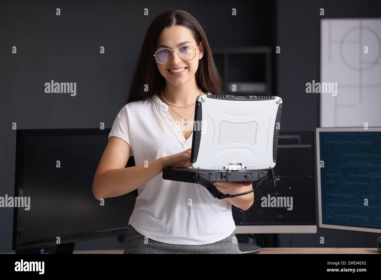 Pretty young female programmer with old laptop working in office Stock ...