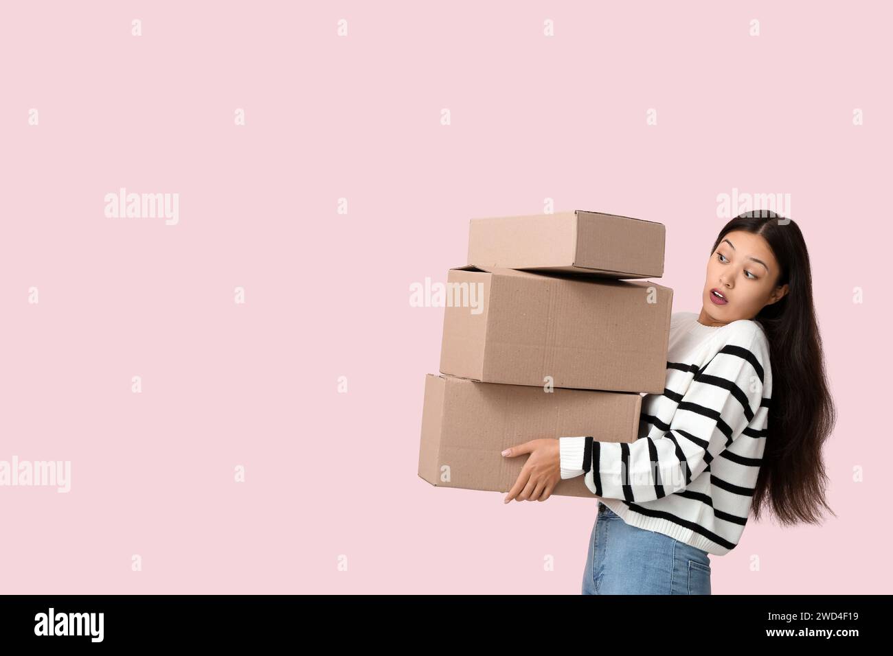 Pretty young woman carrying many parcels on pink background Stock Photo ...