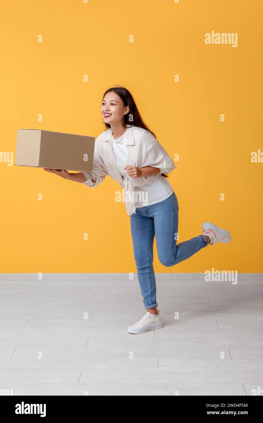 Pretty young woman running with parcel on yellow background Stock Photo ...
