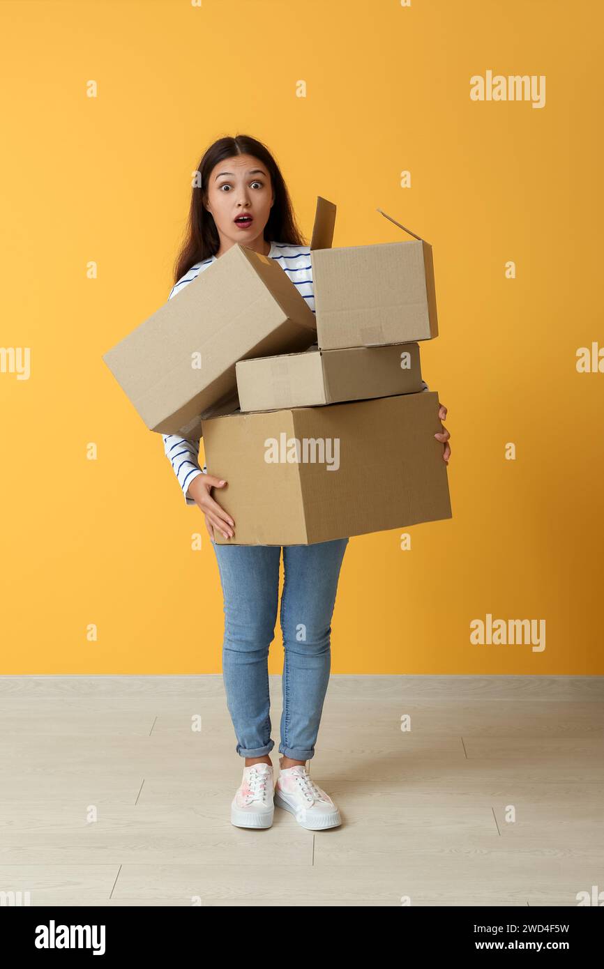 Shocked young woman carrying many parcels on yellow background Stock ...