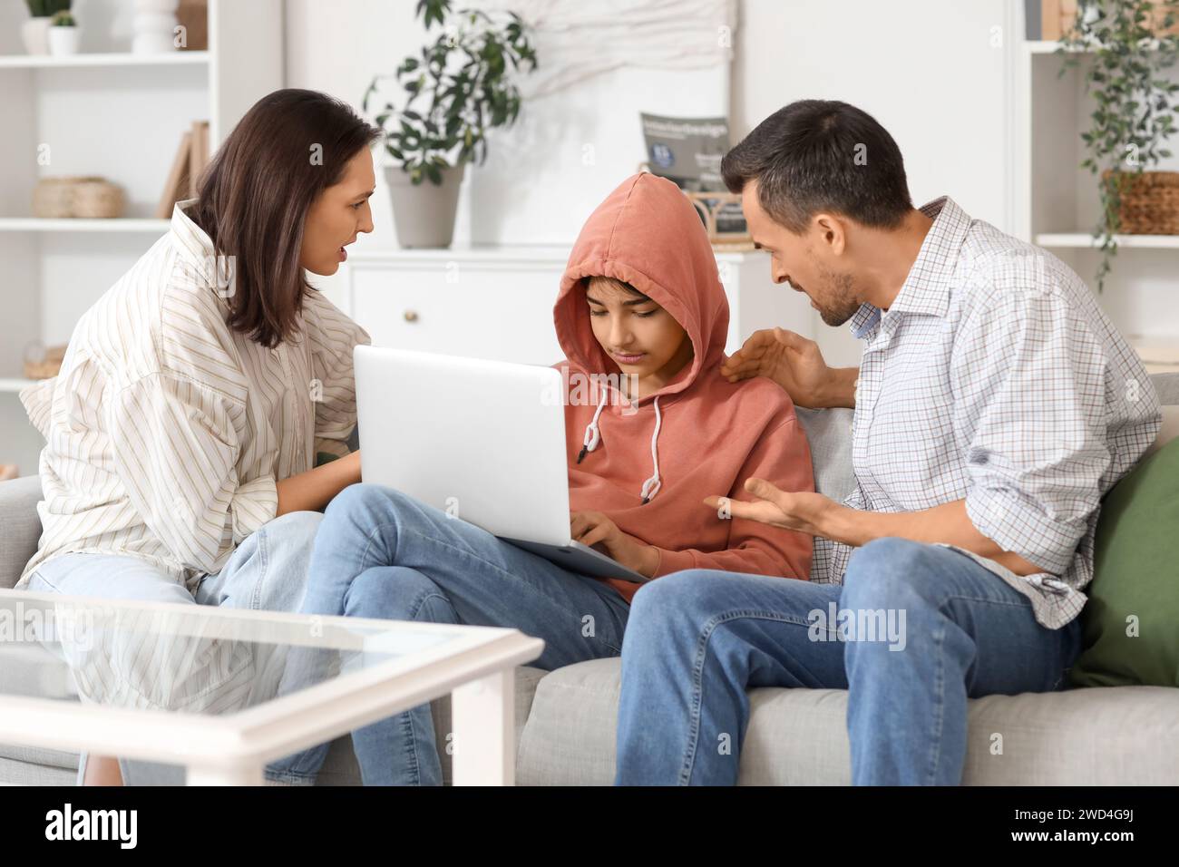Teenage boy with laptop ignoring his parents at home. Family problem ...