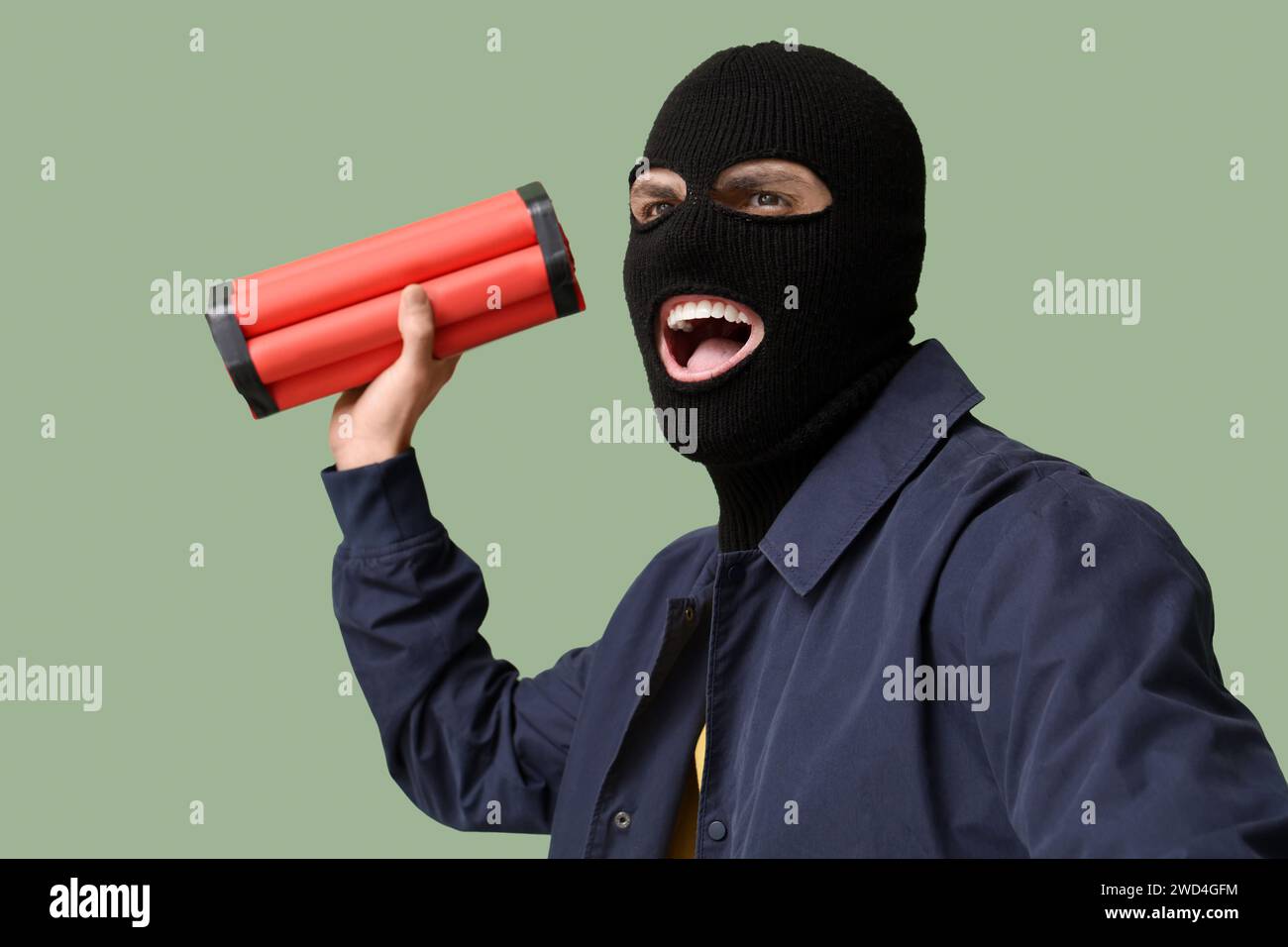 Handsome young happy man in balaclava with bomb on green background ...