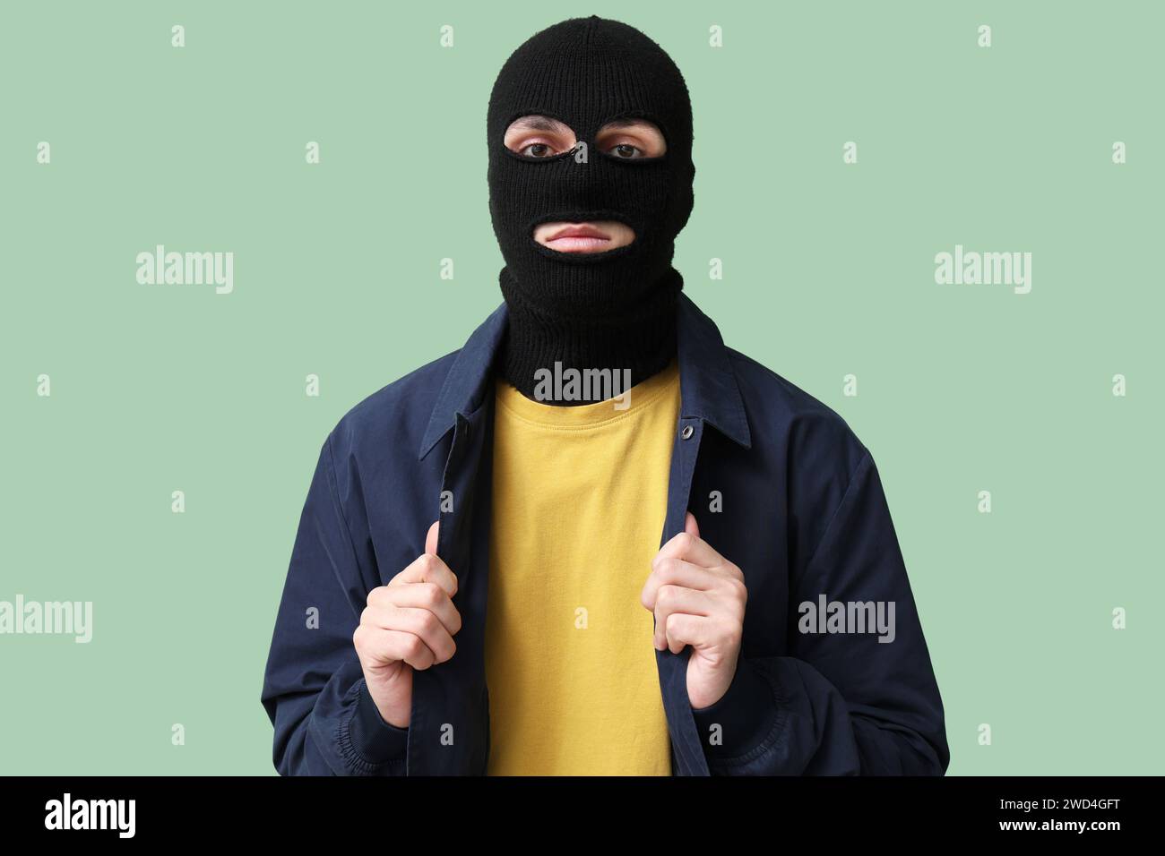 Handsome young man in balaclava on green background Stock Photo - Alamy