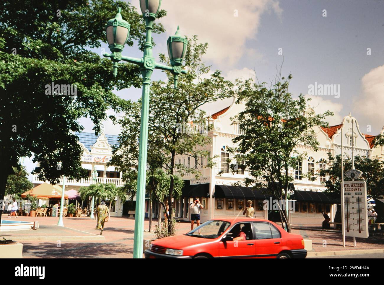 A red car driving through the town square in Oranjestad Aruba, a town ...