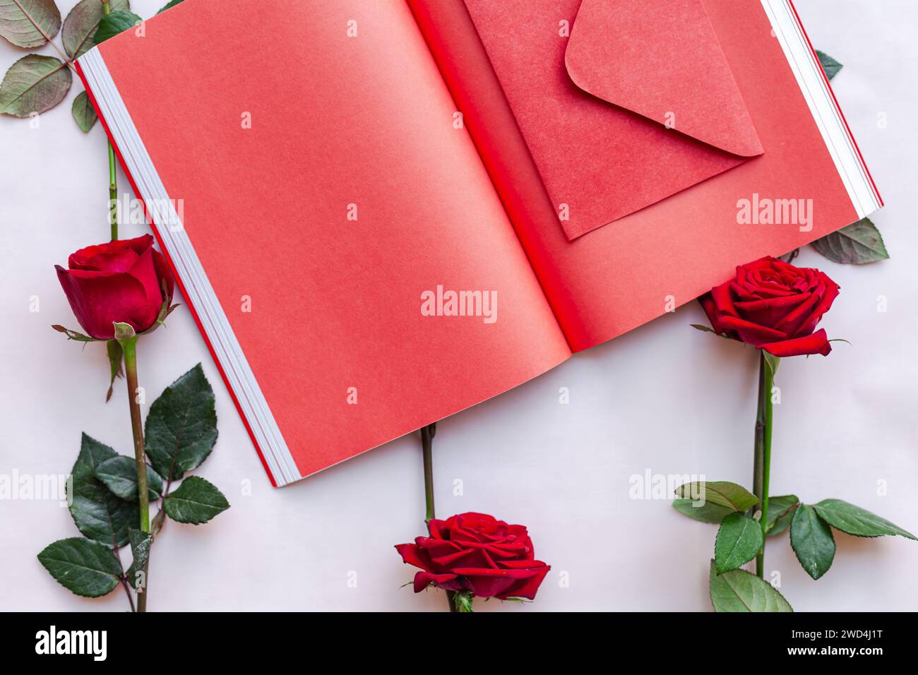 Open book on table with three red roses Stock Photo - Alamy