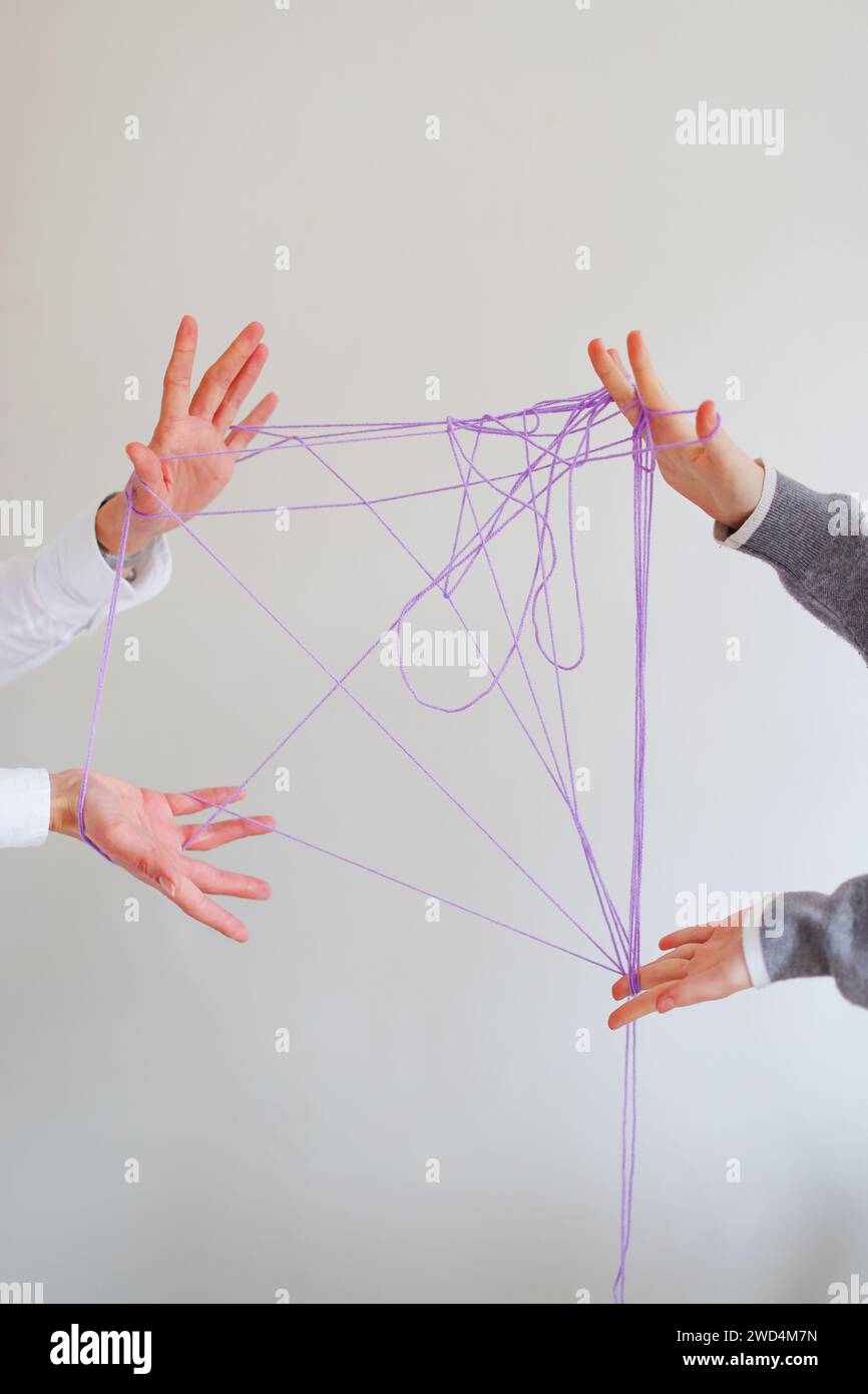 four hands unraveling the rope Stock Photo - Alamy