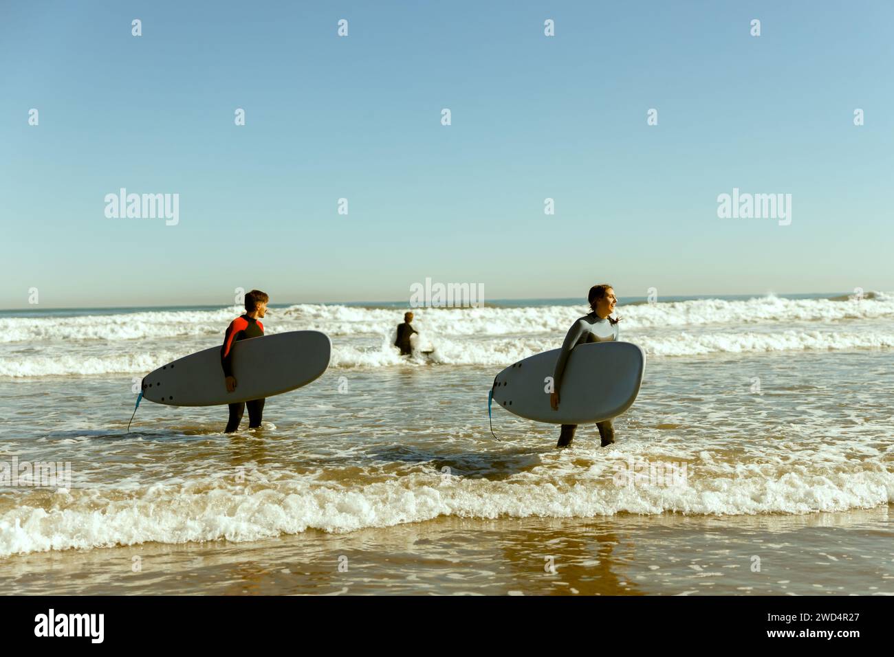 Group of surfers in wetsuit with his surfboards entering out of sea ...