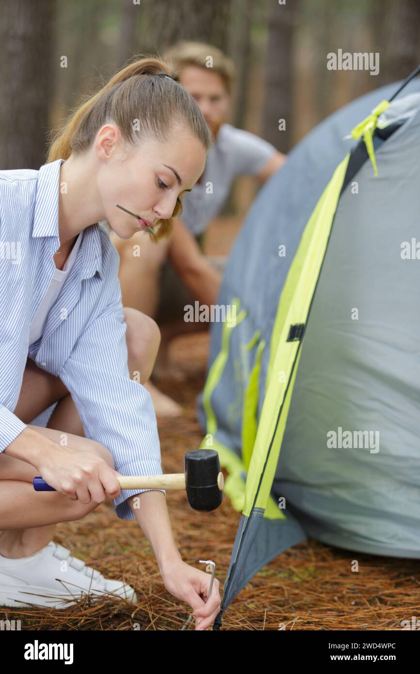 young woman putting up a tent with her friend Stock Photo - Alamy