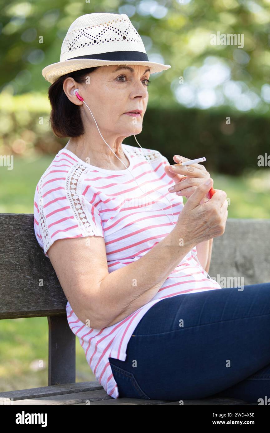 senior woman smoking cigarette on bench in the park Stock Photo - Alamy
