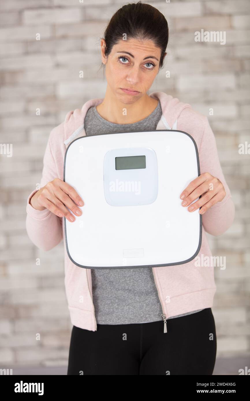 sad woman measuring her weight Stock Photo - Alamy