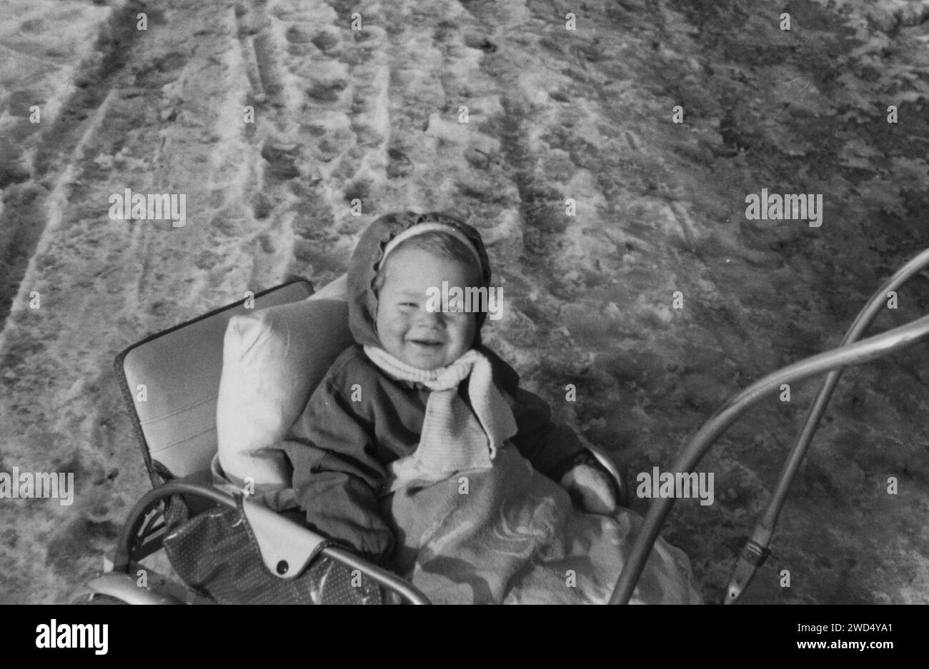An antique photo shows a little Caucasian girl sitting in a stroller ...