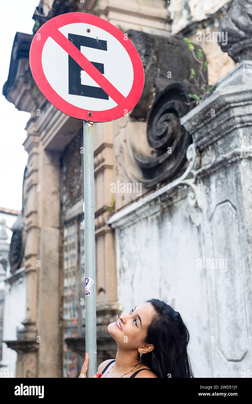 Beautiful, black-haired woman outdoors looking at a sign that says no ...