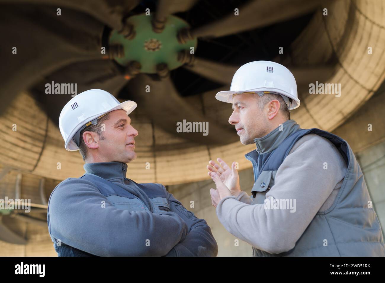 engineers talking under an industrial cooling fan Stock Photo - Alamy