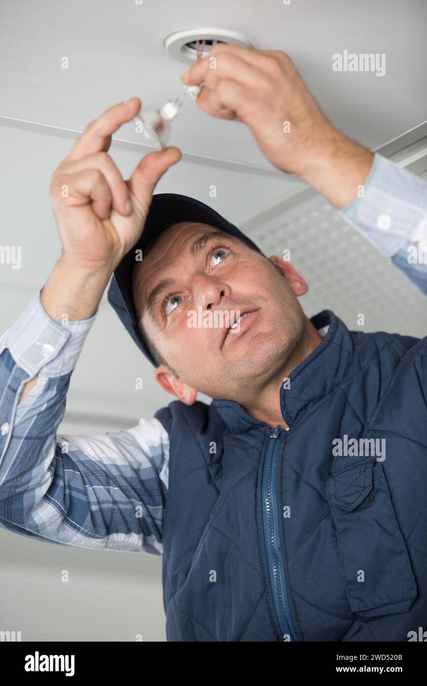 electrician standing on ladder changes a light bulb Stock Photo - Alamy