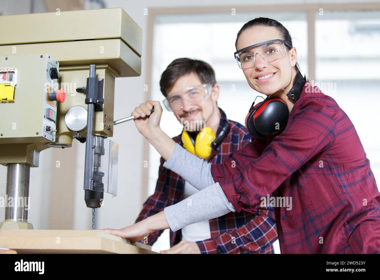 happy engineer instructing female apprentice on use of drill Stock ...