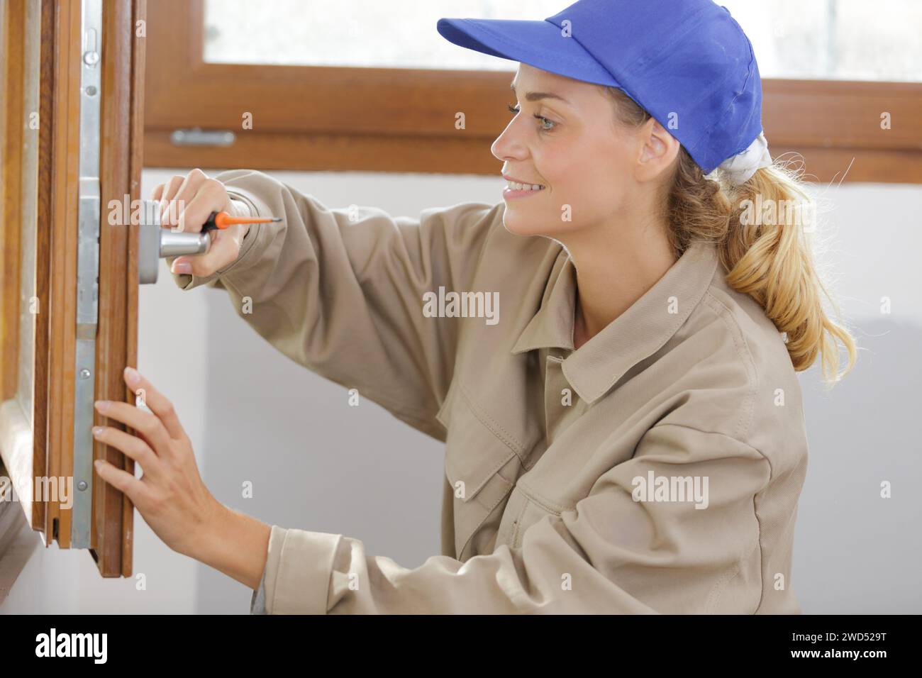 female glazier adjusting wooden window frame Stock Photo - Alamy