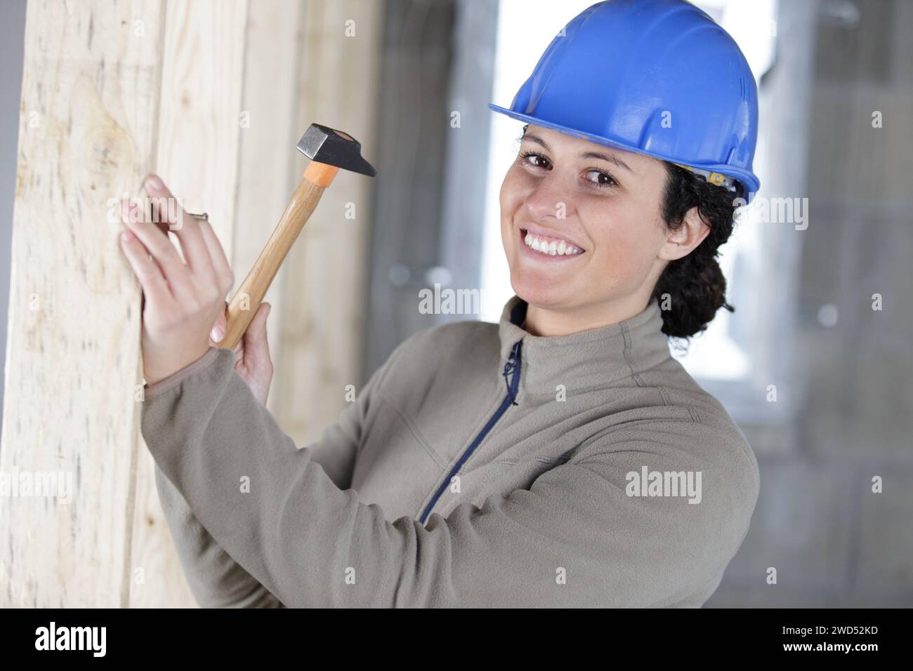 pretty young woman hammering nail into wall Stock Photo - Alamy