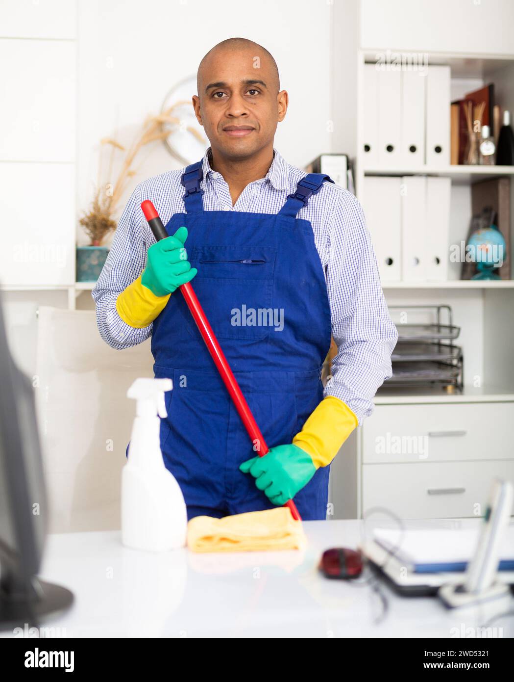 Latin janitor holding cleaning products and tools in office Stock Photo ...