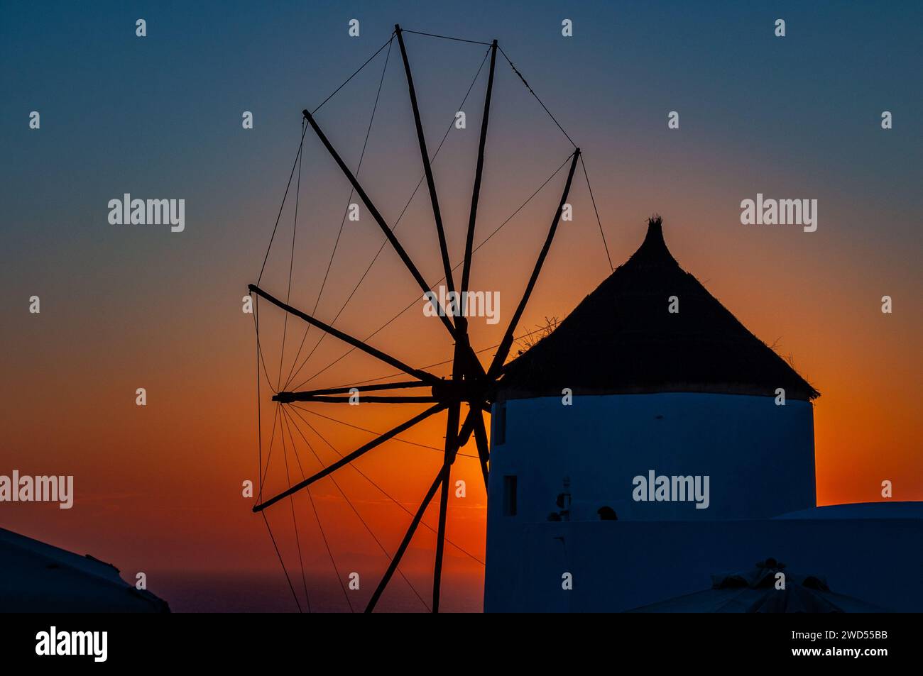 A picturesque scene of a traditional windmill with a red-orange sunset ...
