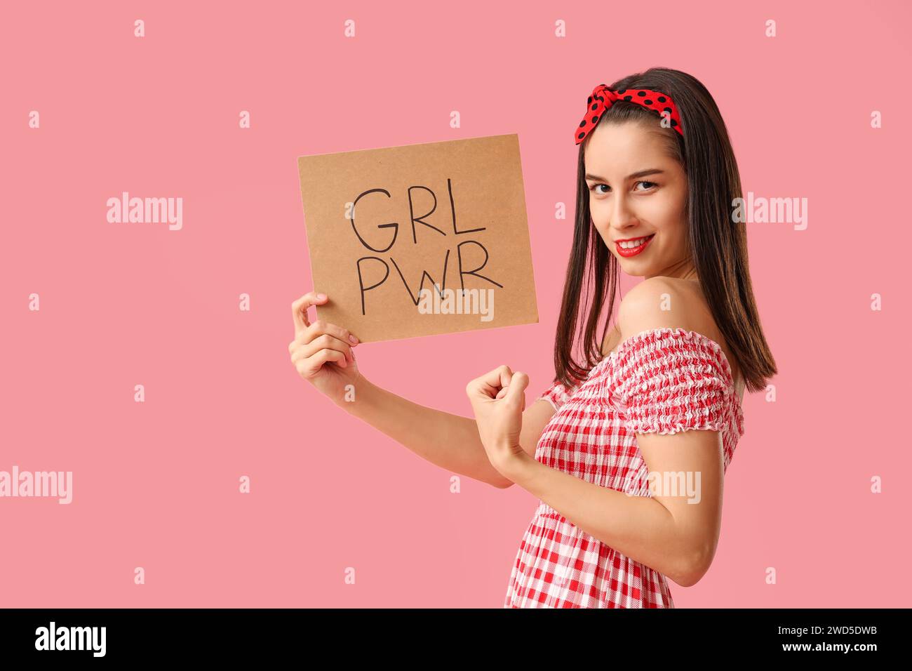 Portrait of strong pin-up woman showing muscles and holding sign with ...