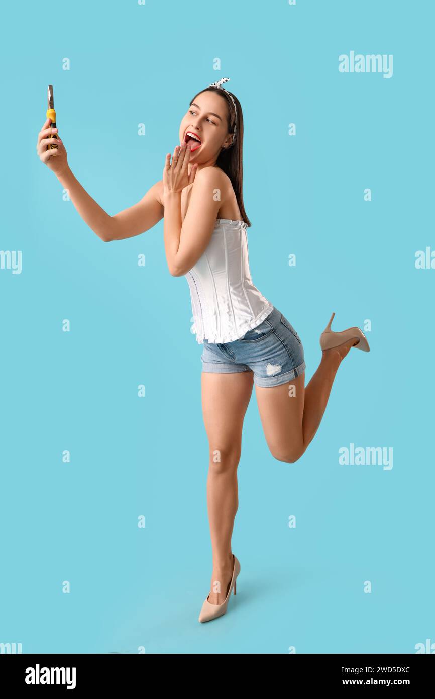 Portrait of young pin-up woman with pliers on blue background. Women's ...