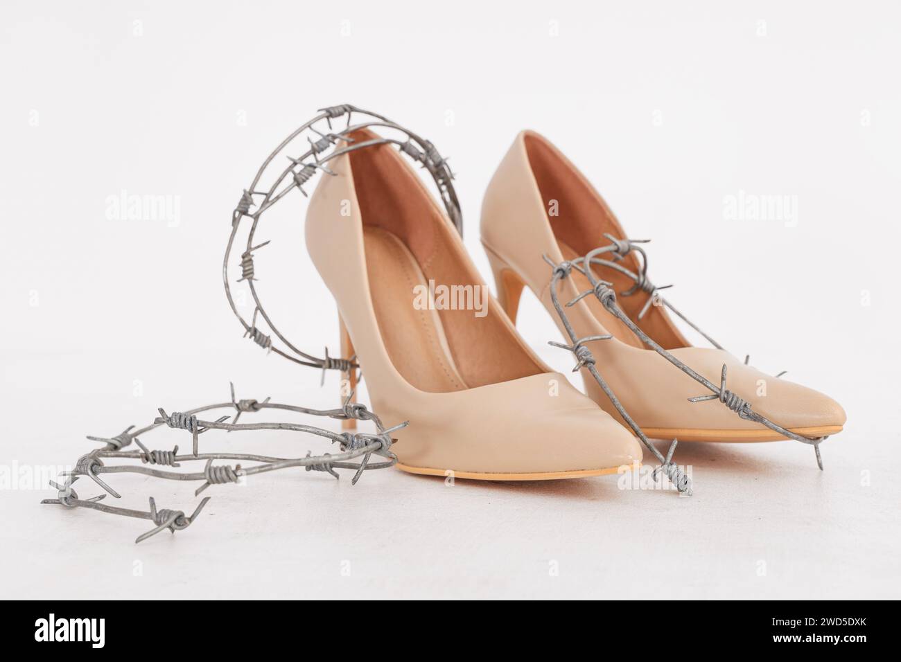 High-heeled shoes wrapped in barbed wire on white background ...