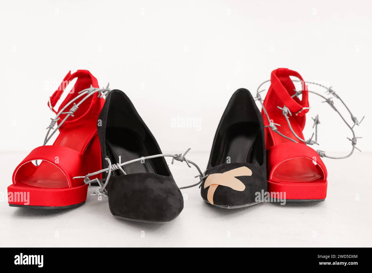 High-heeled shoes with plasters and barbed wire on white background ...