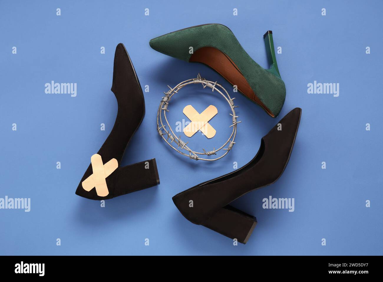 High-heeled shoes with plasters and barbed wire on blue background ...
