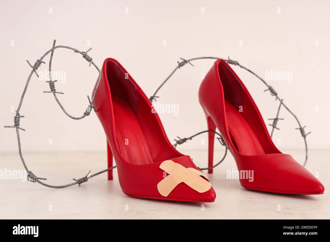 High-heeled shoes with barbed wire and plasters on white background ...