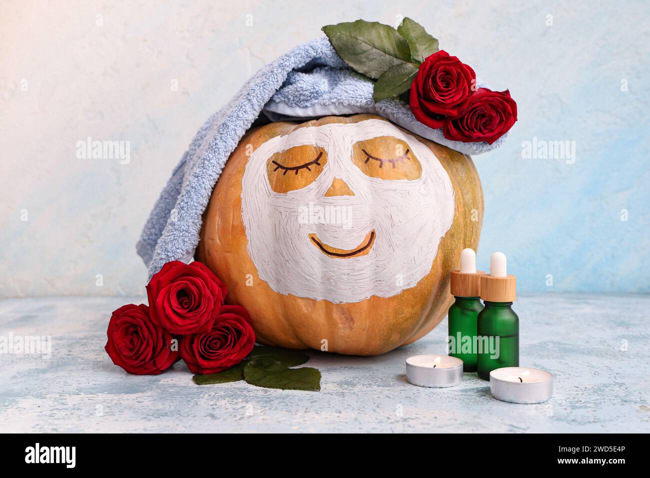 Pumpkin with drawn face, spa supplies, roses and clay mask on grunge ...