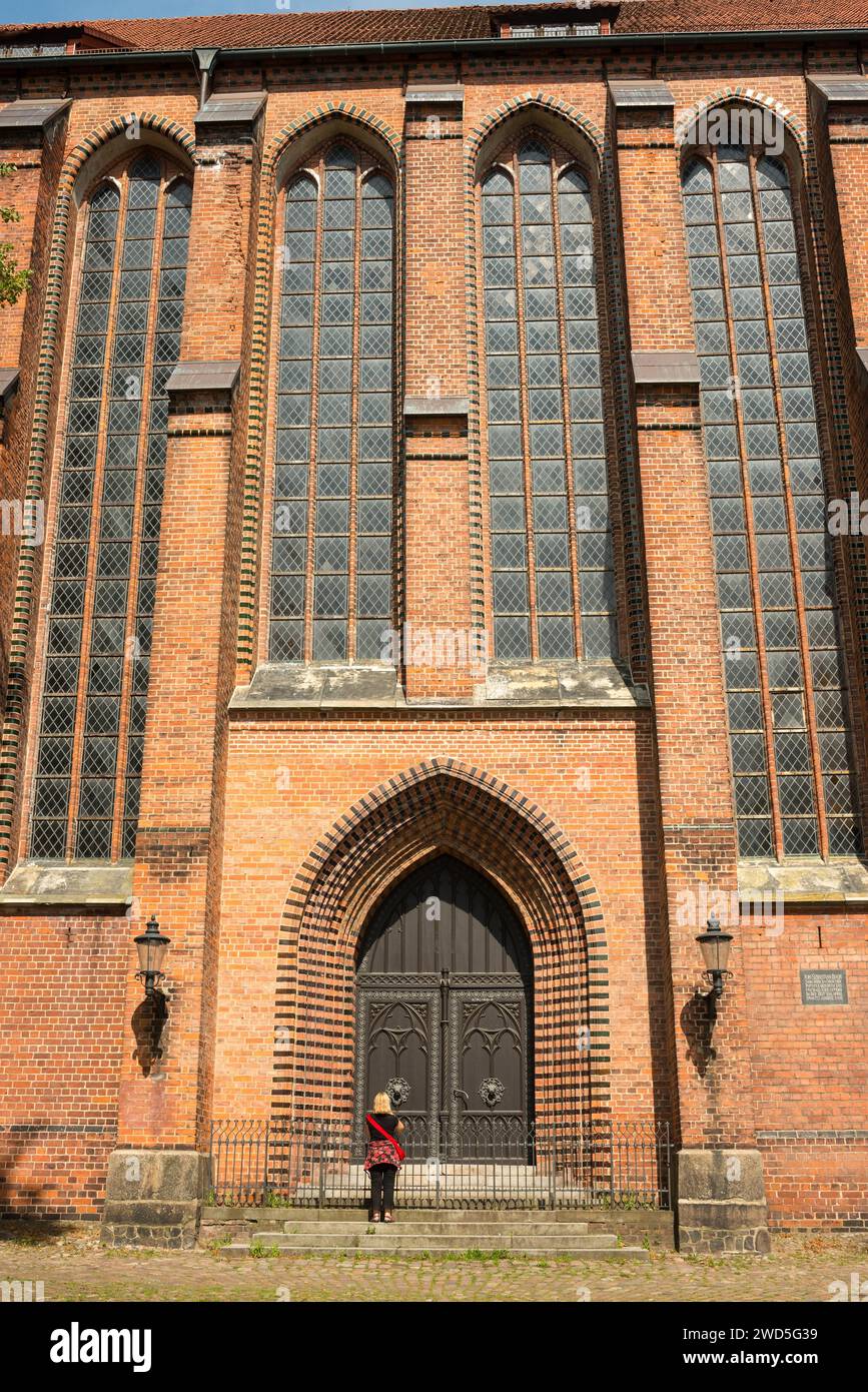 Large brick church with high windows, pointed arches, a person stands ...