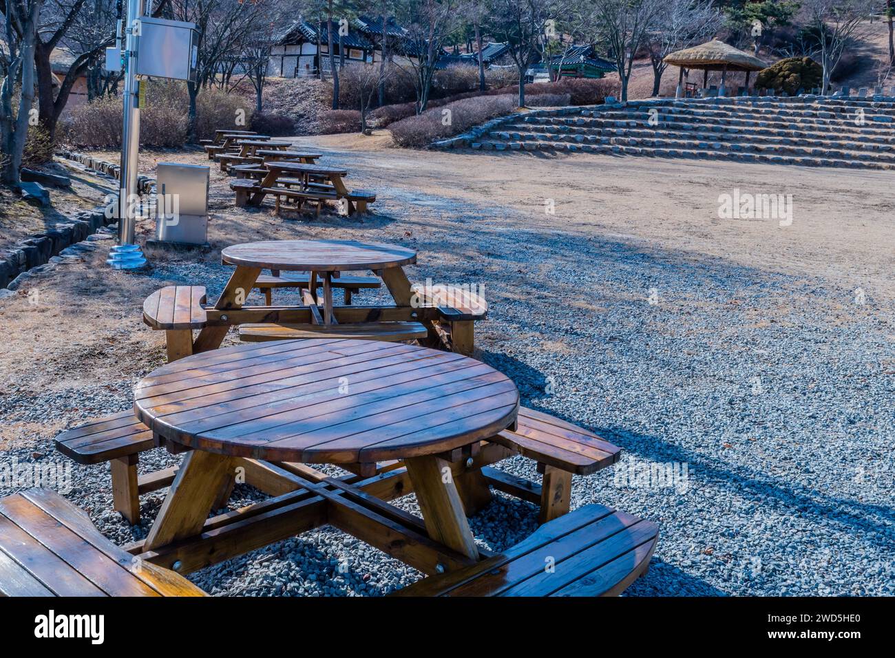 Row of round picnic tables in empty lot with buildings in background ...