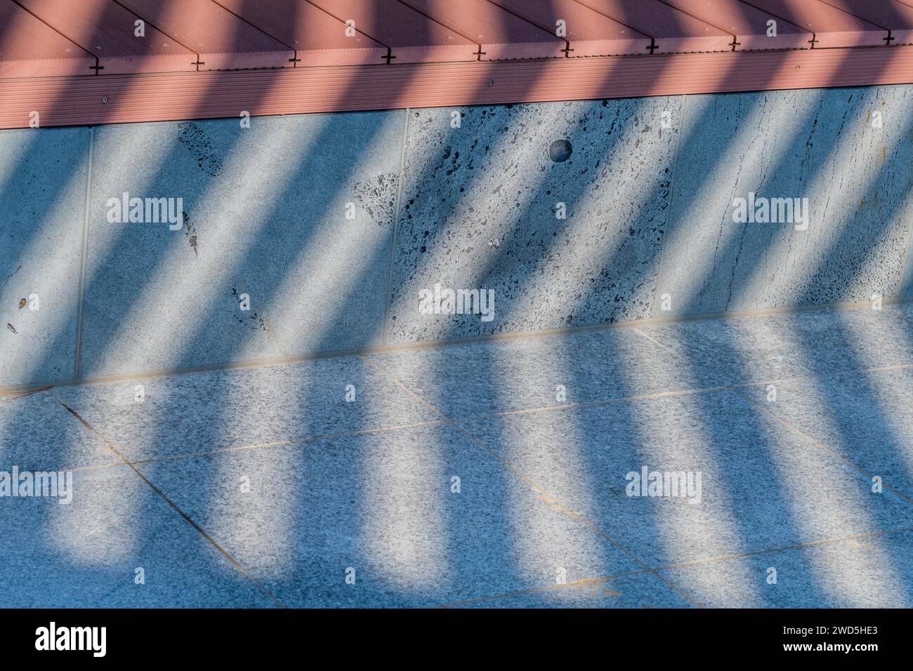 Striped pattern caused by shadows on concrete and wooden bench in local ...