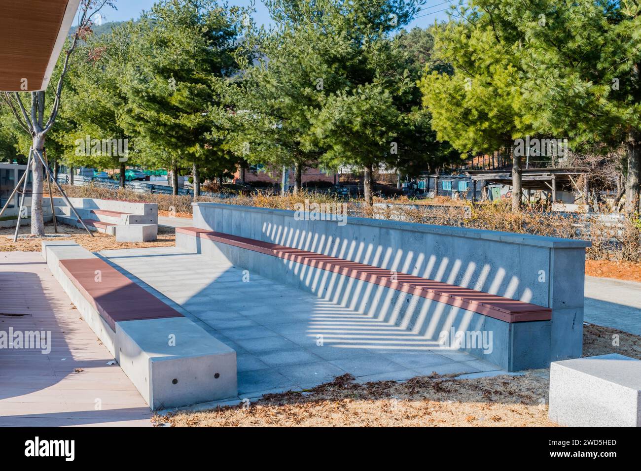 Striped pattern caused by shadows on concrete and wooden bench in local ...