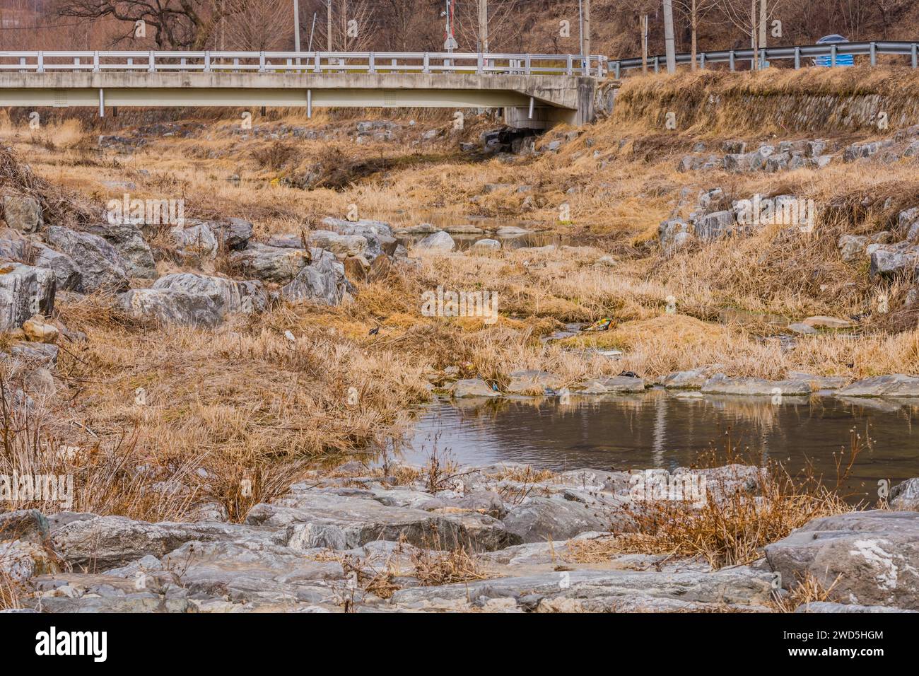 Winter landscape of concrete bridge over small stream with shore of ...