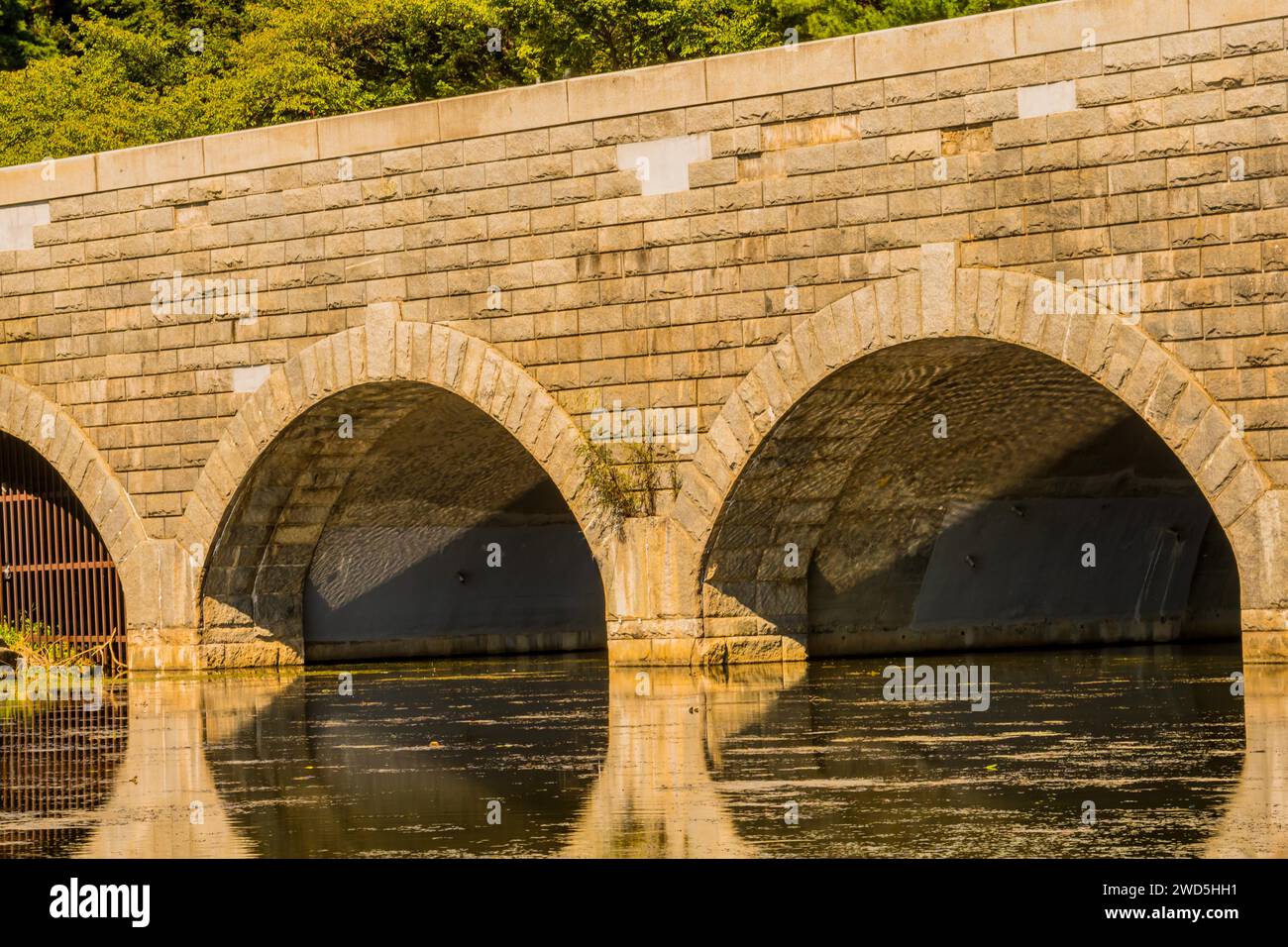 Closeup of large brick bridge with arched tunnels spanning a river ...