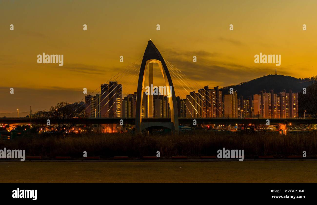 Night view of concrete bridge with triangular arch over a river with ...