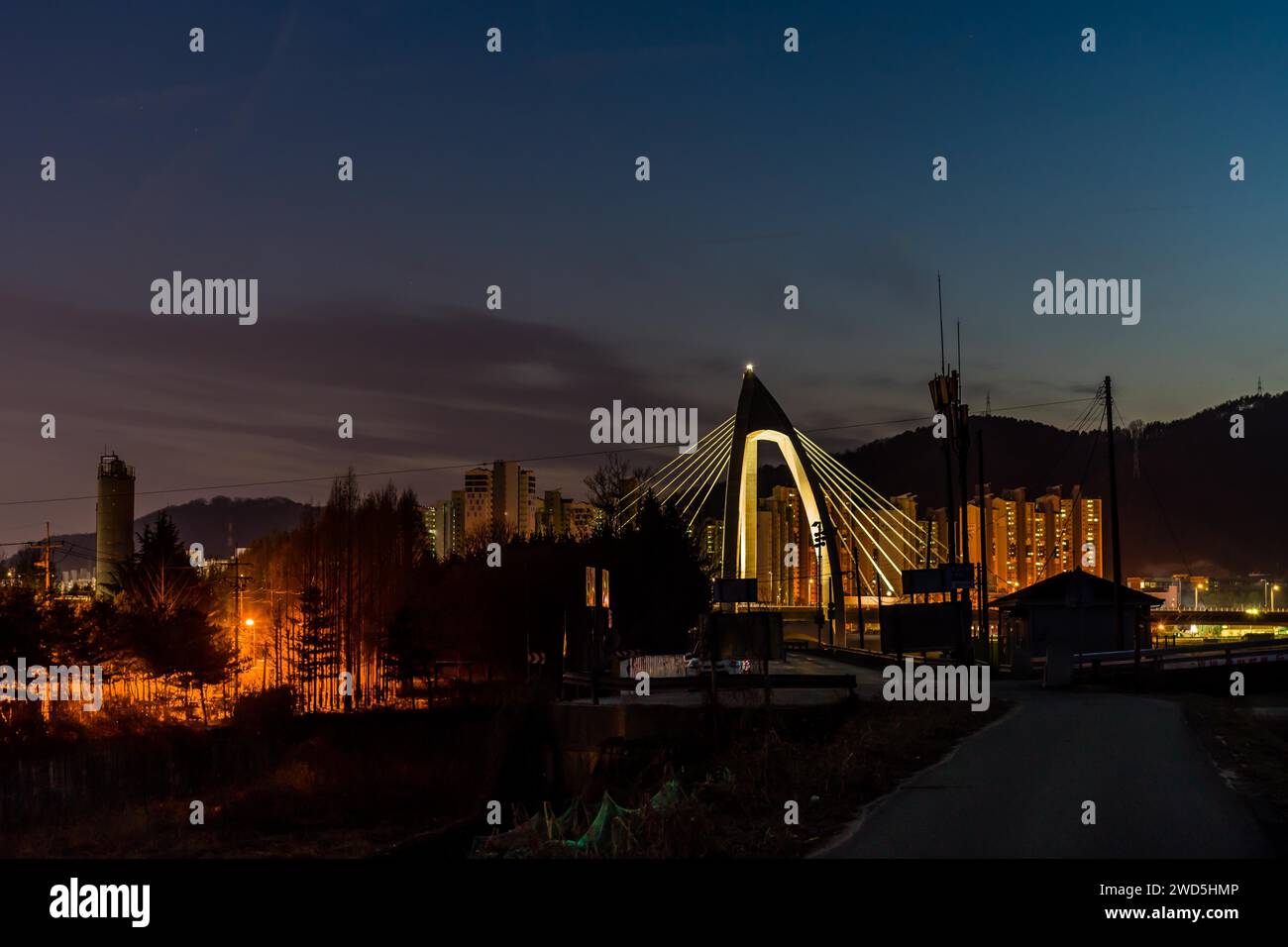 Night view of concrete bridge with triangular arch over a river with ...