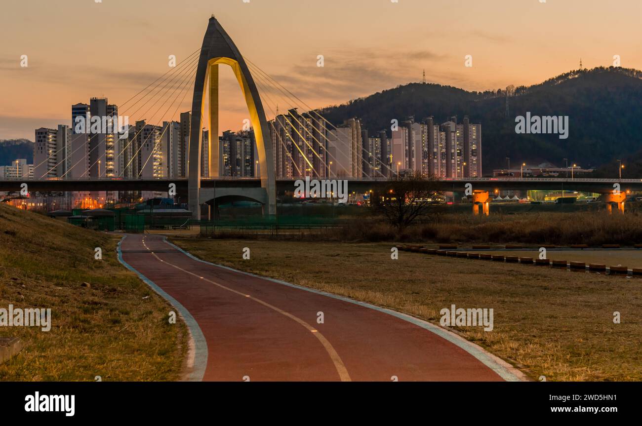Night view of concrete bridge with triangular arch over a river with ...
