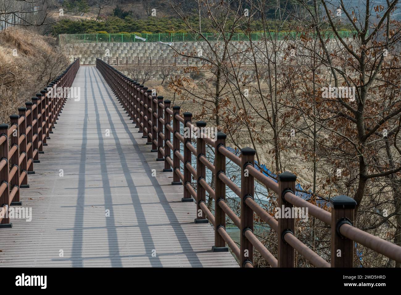 Wooden pedestrian bridge with shadow of railing in mountainside park on ...