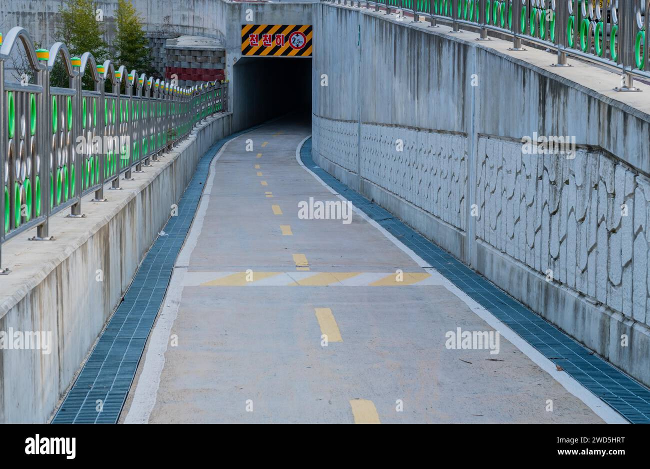 Two lane bicycle path and underpass with caution sign that says SLOW in ...