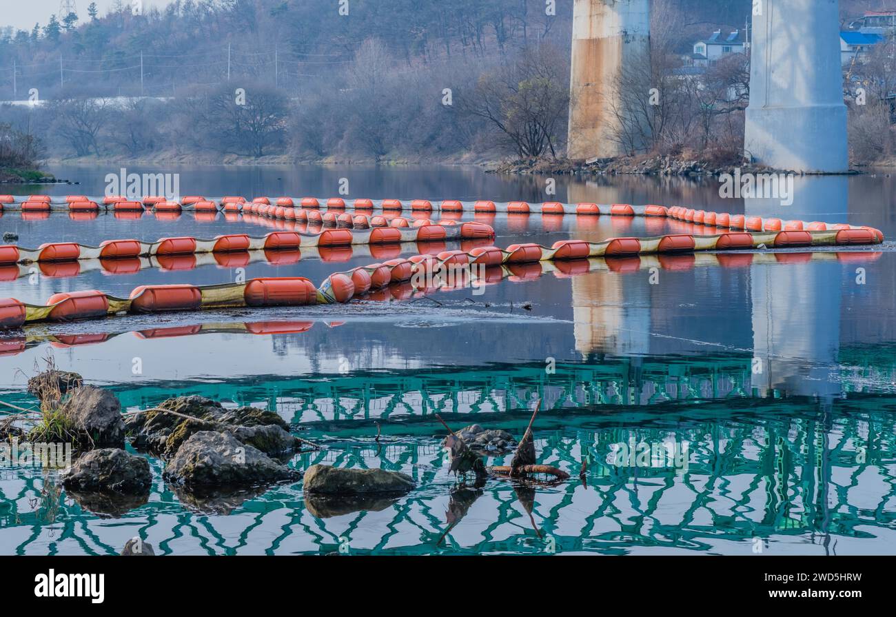 Reflection of green truss railway bridge in river where orange floats ...