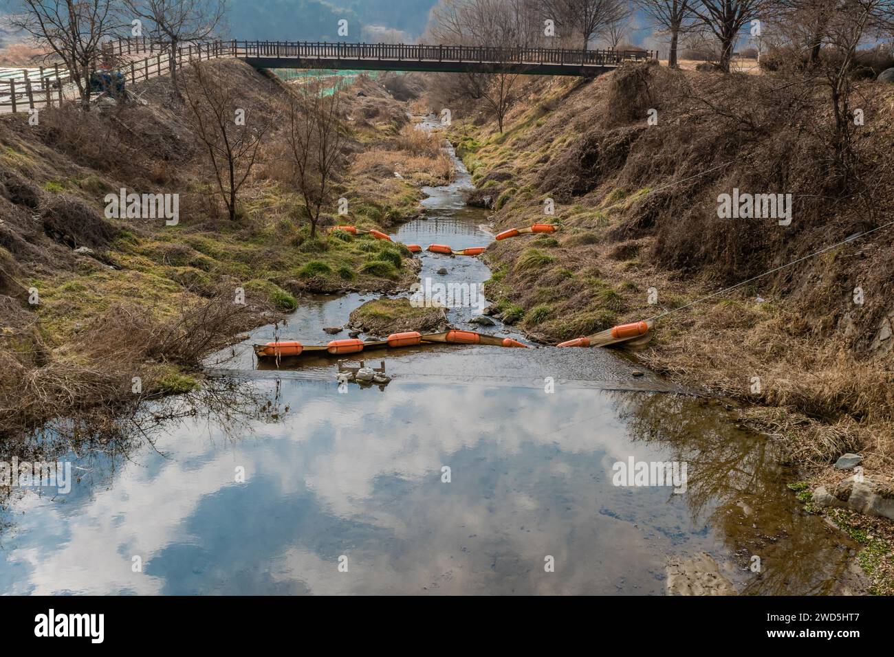 Small stream running under wooden footbridge in rural public park on ...