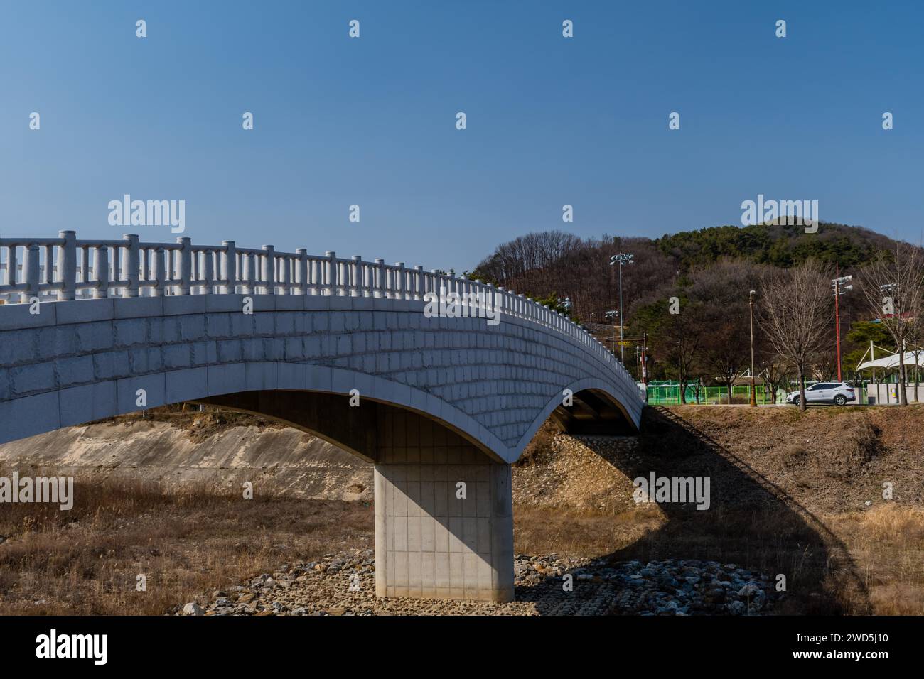 White concrete block pedestrian bridge in public park under clear blue ...