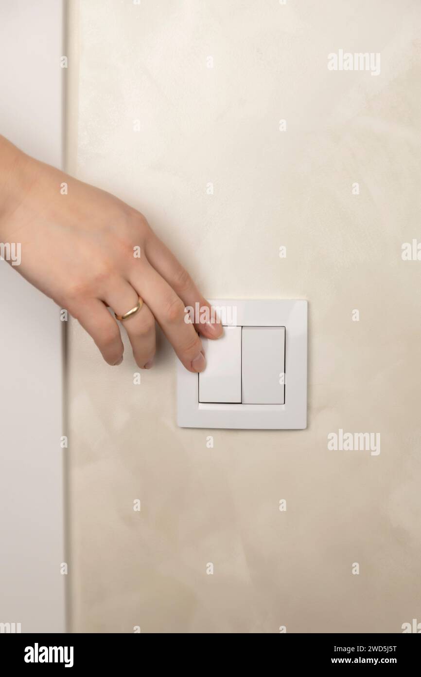 A woman's finger turns on the light switch at home. Close-up A woman ...