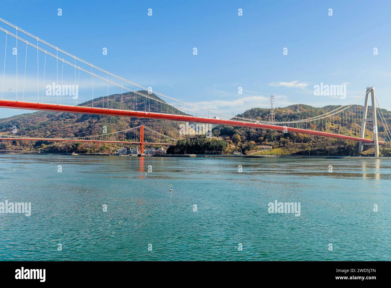 Suspension bridges over large body of water with mountains in ...