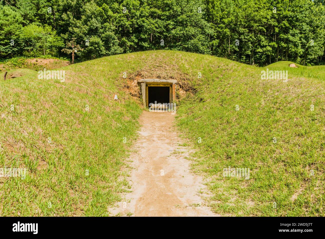 Unmarked mound tomb with dirt path leading to concrete opening on dry ...