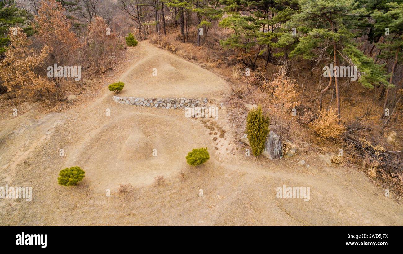 Low altitude aerial view of small oriental burial mounds in a woodland ...