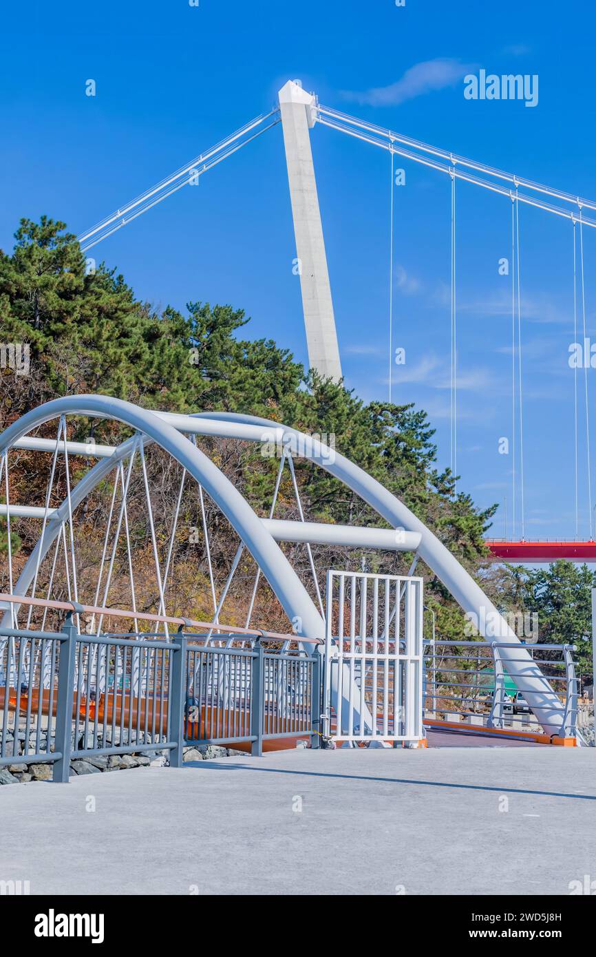 Small pedestrian bridge with trees and suspension bridge pylons in ...