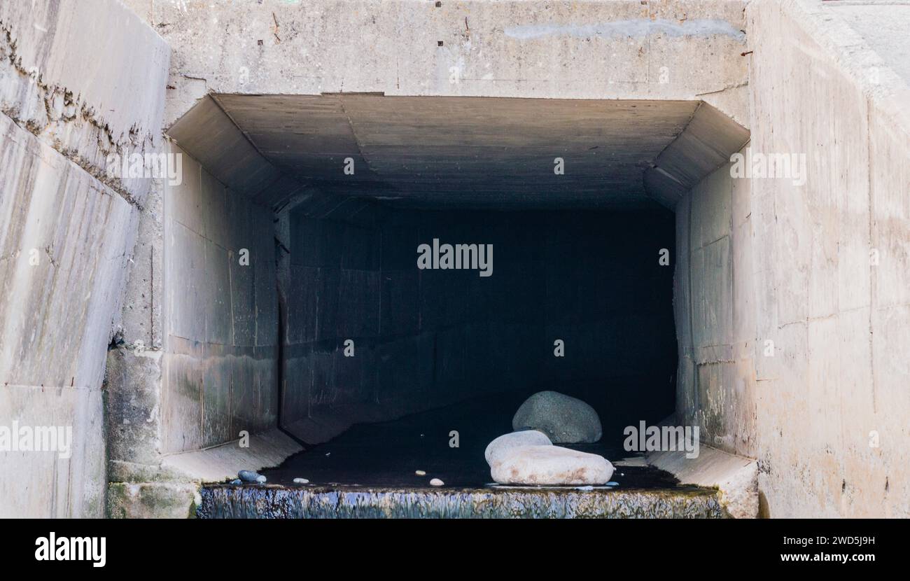 Concrete tunnel at Pebble Beach in South Korea with water running onto ...